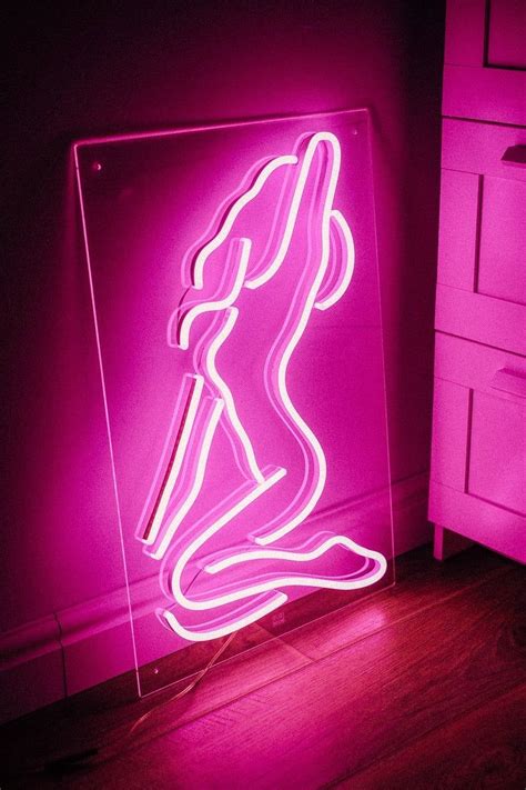 A Neon Sign Sitting On Top Of A Wooden Floor Next To A Pink Dresser And Drawers