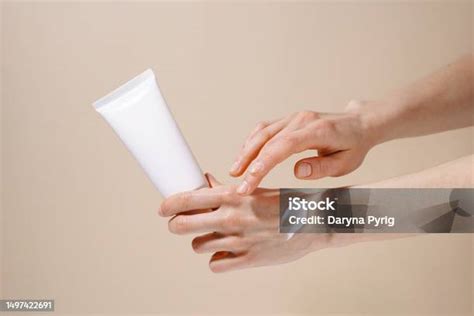 하얀 모형 항아리를 들고 베이지색 격리된 배경에 크림 샘플 견본을 바르고 있는 여성의 손 아름다움과 미학 보습 및 피부 관리의 개념 디자인을 위한 이미지 가꿔주기에 대한