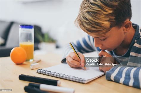 노트북에 연필로 그림을 그리는 학생 종이에 숙제를 쓰고 있는 소년 아이는 연필을 들고 집에서 만화를 그립니다 테이블에 앉아 십대 그림 교육 예술 인재 능력 개념 소년에 대한