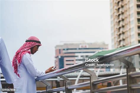 스마트 폰 응용 프로그램을 사용하는 이슬람 남자는 스마트 폰 무슬림 현대 아랍 도시를 들고 손에 일정 의제를 구성합니다 아랍 남성 착용 히잡과 무슬림 정장 드레스 보내는