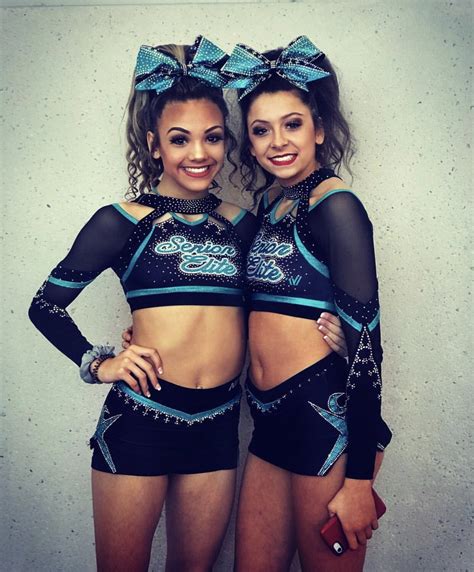 Two Cheerleaders Posing For The Camera With Their Arms Around Each Other S Backs