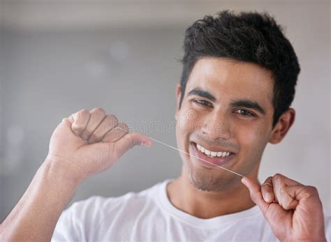 I Know Whats Good For My Teeth Portrait Of A Happy Young Man Flossing His Teeth At Home Stock