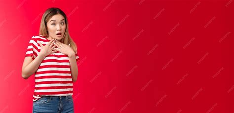 Шокированная безмолвная гламурная блондинка азиатская девушка прижимает ладонь к груди удивленно