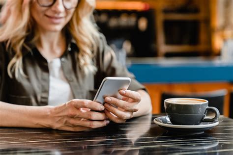 카페 레스토랑에서 커피를 마시면서 전자 뱅킹 원격 작업을 위해 스마트 폰 휴대 전화를 사용하여 들고있는 백인 젊은 여성의 집중 된 크롭 클로즈업 샷 30 34세에 대한 스톡