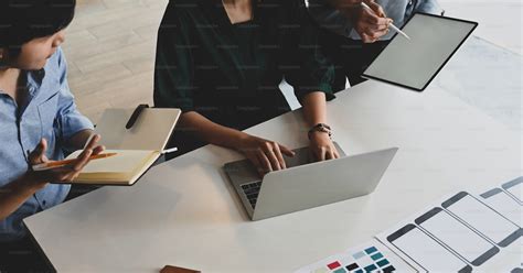 그래픽 디자인 팀이 함께 작업하고 스마트폰의 새로운 기능에 대해 브레인스토밍하는 상위 뷰 이미지입니다 협업 공동 작업자 회의