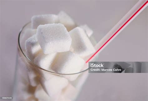 설탕 큐브 및 포도 당 중독 건강 하지 못한 초과 칼로리와 영양 칼로리 학대의 흰색 배경에 고립 밀 짚의 가득 차 있는 다과 유리의 개념적 매크로 정 이미지 0명에 대한