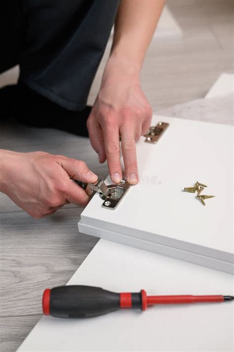 Assembling Furniture A Worker Inserts A Hinge Into A Wooden Closet Door Adjustment Of Fittings