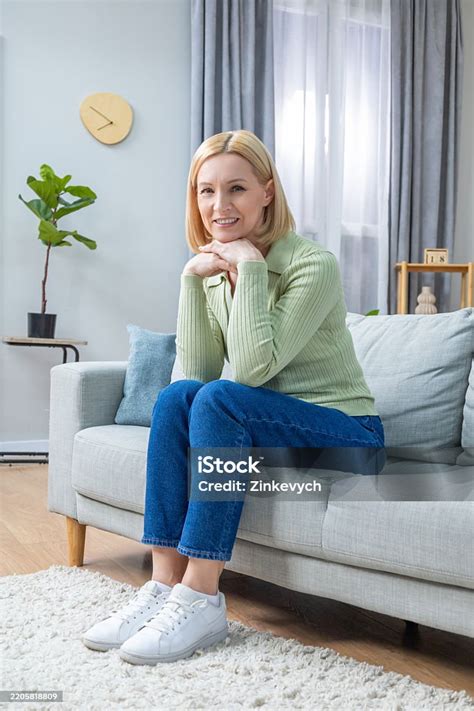예쁜 중년의 금발 여자가 소파에 앉아서 만족스러워 보인다 40 44세에 대한 스톡 사진 및 기타 이미지 40 44세 50 59세 Hrt 제 Istock