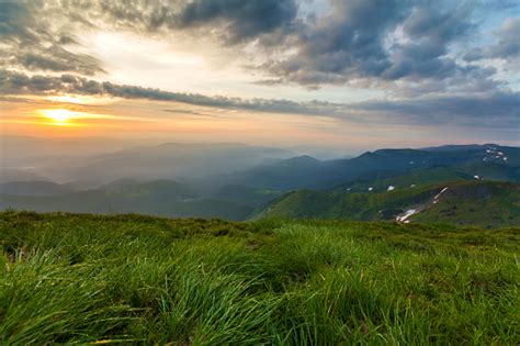 넓은에 마운틴뷰 여름 아침 안개로 덮여 빛나는 오렌지 태양 높이 푸른 흐린 하늘에 녹색 잔디 언덕 부드러운 잔디와 먼 산 범위