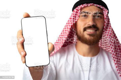 하얀 배경에 고립 된 휴대 전화를 보여주는 전통적인 옷을 입은 젊은 아랍 무슬림 남자 25 29세에 대한 스톡 사진 및 기타 이미지 25 29세 공란 광고 Istock