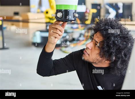 An Engineer Closely Examining A Robotic Gripper Arm In A High Tech