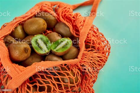 플랫 누워 메쉬 식료품 쇼핑 환경 친화적 인 가방 블루 캔버스 배경에 키위 제로 폐기물 Cconcept 지역 농민 시장 쇼핑몰 상단보기 복사 공간 플라스틱 무료 항목 0에