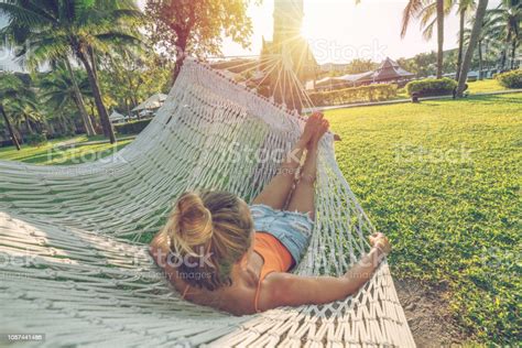 젊은 여자 야자수와 푸른 잔디 정원 고요한 환경을 즐기고 머리 뒤에 열 대 기후 손에 해먹에 휴식 사람들이 여행 휴가 개념 휴식
