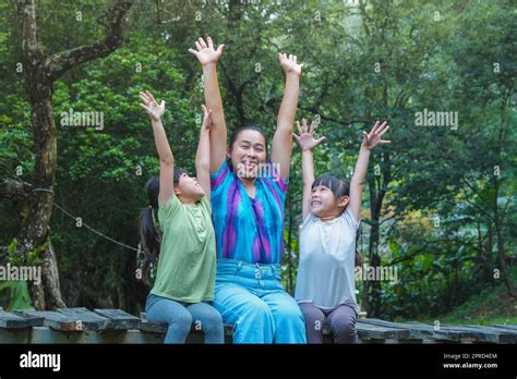 Glückliche junge Mutter mit kleinen Mädchen im Sommer auf einer Holzbrücke in der Nähe des