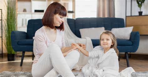 어린 예쁜 엄마는 귀여운 딸의 팔 상처에 접착 석고 붕대를 바르고 집에 앉아 거실 바닥에 앉아 위생 절차를 돌보고 있습니다 사진 Unsplash의 우크라이나 이미지