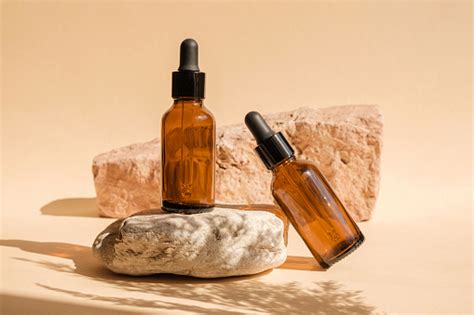 돌 위에 서있는 어두운 호박색 유리 병 자연 스킨 케어 Spa 뷰티 제품 디자인 베이지 색 배경에 미네랄 유기농 오일 화장품 모형 기름진 피펫 얼굴과 몸 치료 정면보기 0