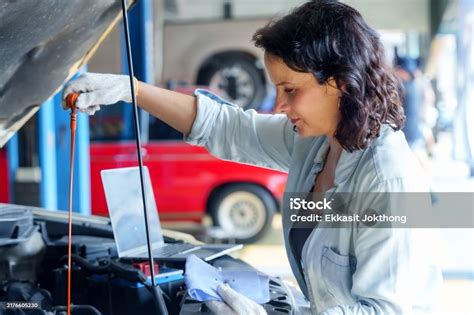 자동차 정비소에 서서 장갑과 캐주얼 한 옷을 입고 수동 자동차 유지 보수 기술 및 전문 지식을 착용하면서 자동차 엔진의 오일