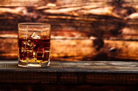 유리에 얼음 이나 브랜디와 오래 된 나무 배경에 사각형 유리병과 위스키 유리에 얼음을 가진 위스키 위스키 또는 코냑 선택적 초점