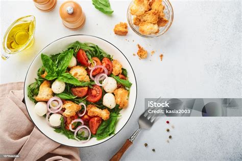 판자넬라 빵 샐러드 토마토 모짜렐라 공 바질 양파 빵을 밝은 회색 배경에 곁들인 이탈리아의 전통 음식 전통 이탈리아 요리 맨 위 보기입니다 공간을 복사합니다 크로톤 큐브