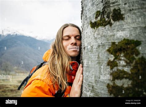 Blond Man Touching Tree Trunk Stock Photo Alamy