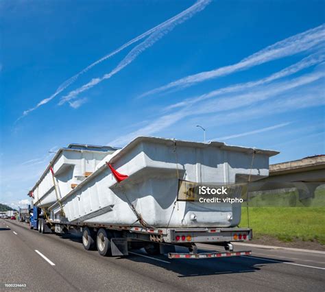 여러 라인 고속도로에서 달리는 뒤쪽에 특대 하중 표시가 있는 플랫 베드 세미 트레일러에 대형 화물을 운송하는 파란색 큰 장비