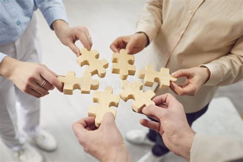 Close Up Photo Hands Of People Holding Diverse Pieces Of Wooden Puzzle Team Assembling Jigsaw