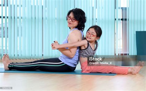 실내 스튜디오에서 요가 운동을하는 어머니와 딸 함께 요가를 연습하는 스포티 한 가족 요가 포즈를 취하도록 자녀를 돕고 가르치는
