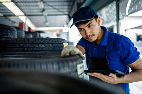 디지털 태블릿을 사용하여 차고의 재고 타이어를 확인하고 예비 부품을 교체하고 자동차의 주행 거리를 확인하고 점검 및 유지 보수 서비스 개념을 확인하는 자동차 정비공 25