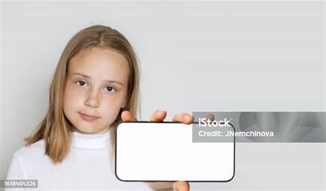 귀여운 아이 소녀 새로운 응용 프로그램 또는 모바일 웹 사이트 모형 배너에 대한 빈 흰색 화면 디스플레이와 큰 빈 스마트 폰을