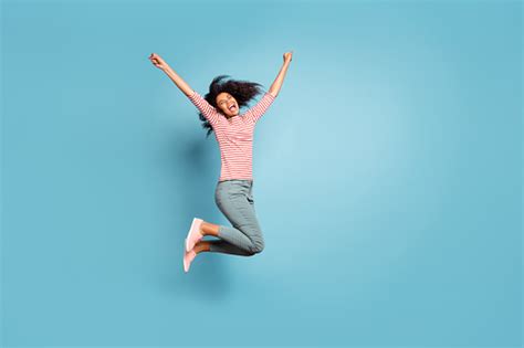 스트라이프 티셔츠에 파란색 파스텔 색상 배경을 통해 고립 된 점프 행복으로 비명을 지르는 쾌활한 귀여운 좋은 여자 친구를 외치는 전체 길이 바디 사이즈 프로필 측면 사진 T