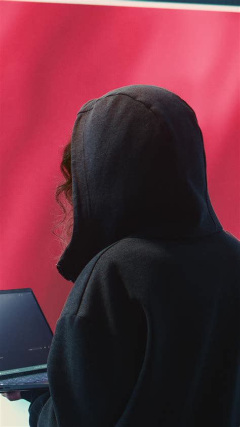 Vertical Chinese Hacker Working In Governmental Hacking Room With Chinese Flag On A Big Screen