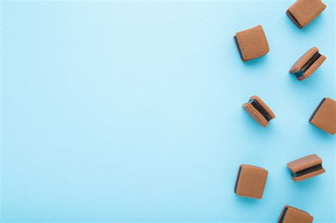 밝은 파란색 테이블 배경에 다크 초콜릿을 곁들인 브라운 젤리 구미 사탕 파스텔 색상 달콤한 스낵 근접 촬영 텍스트의 빈