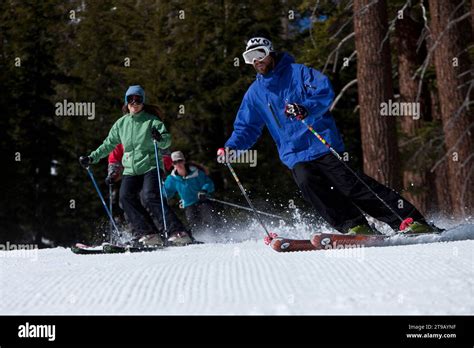 Low Angle Perspective Of A Ski Instructor Skiing With His Class Behind