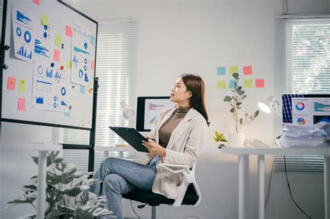 화이트보드에서 재무 차트를 분석하고 클립보드와 펜을 들고 컴퓨터 화면의 데이터를 검토하고 전략 계획에 집중하는 전문 아시아 사업가 20 29세에 대한 스톡 사진 및 기타