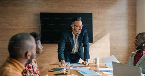 기업 회의 중 아프리카 동료들 앞에서 회의실 테이블 위에 서 있는 사업가 사진 Unsplash의 가로 이미지