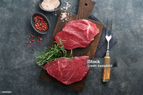 생 쇠고기 스테이크 어두운 콘크리트 배경의 도마에 로즈마리 소금 후추를 곁들인 차돌박이 생 신선한 립아이 스테이크 생 쇠고기 스테이크와 요리 용 향신료 0명에 대한 스톡
