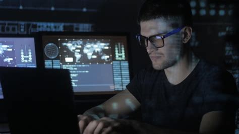 Hacker Programmer In Glasses Is Working On Computer While Blue Binary Code Characters Reflect On