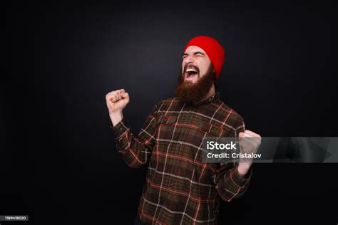 빨간 모자를 쓴 수염을 기고한 남자의 사진 눈을 감고 비명을 지르며 어두운 벽을 통해 축하 감정에 대한 스톡 사진 및 기타 이미지 Istock