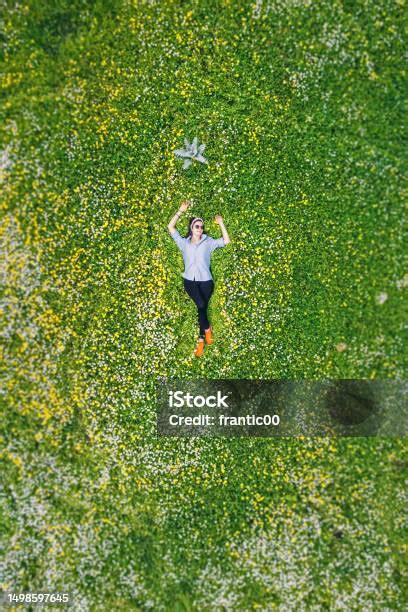 Aerial View Of A Happy Woman Lying On A Grass With Wildflowers In Park