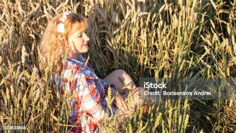갈색 머리를 한 소녀가 석양을 배경으로 밀밭에 앉아 있다 소녀는 밀의 귀를 손에 들고 태양을 바라본다 가을에 대한 스톡 사진 및 기타 이미지 Istock