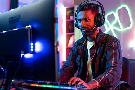 집에서 헤드폰으로 이야기하여 컴퓨터에서 온라인 비디오 게임을하는 흥분된 프로 게이머 엔터테인먼트 게임 중독 및 사이버 공간의 개념 비디오 게임에 대한 스톡 사진 및 기타