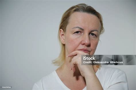 단순한 실제 여자의 슬프고 차분한 모습 도색되지 않은 머리카락은 자기 관리가 필요합니다 손으로 눈을 내리깔고 그녀는 턱을 잡고 흰색 배경에 카메라를 봅니다 귀여운에 대한