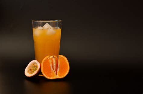 검은 배경에 얼음과 섞인 열대 과일의 키 큰 유리 잘 익은 오렌지 조각과 패션 프루트가 근처에 있습니다 가득 찬에 대한 스톡 사진 및 기타 이미지 Istock