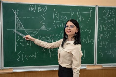 Young Pretty Female Teacher Writing On A Chalkboard Completing Mathematical Equations In