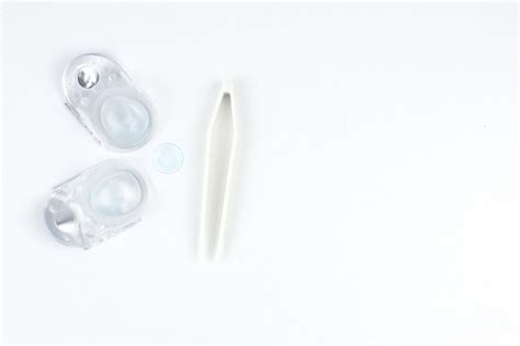 일회용 콘택트렌즈 용기 두 개와 콘택트블루 소프트 렌즈와 베이지색 핀셋이 흰색 배경에 왼쪽에 놓여 있으며 텍스트를 위한 공간이 클로즈업되어 있습니다 안과 시력 시력 교정의