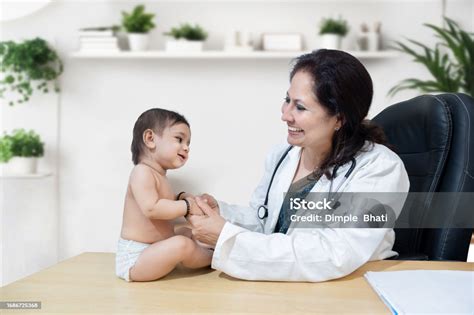 미소 짓는 젊은 인도 여성 의사가 진료소에서 어린 아기 소녀를 검진하고 있다 소아과 의사에게 정기적으로 검사하십시오 아이의 건강 관리 및 의료 개념입니다 소아과 의사에 대한