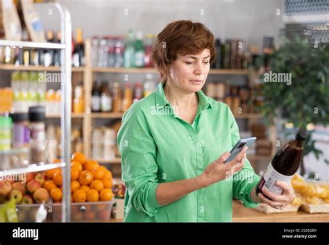 Female Shopper Scans A QR Code On A Pomegranate Juice Label Using Smartphone Stock Photo Alamy