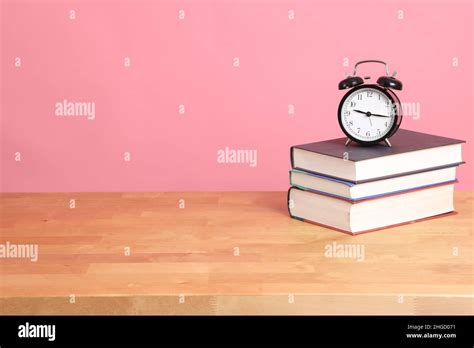 The Analog Clock Setting On The Stack Of Book With Color Background