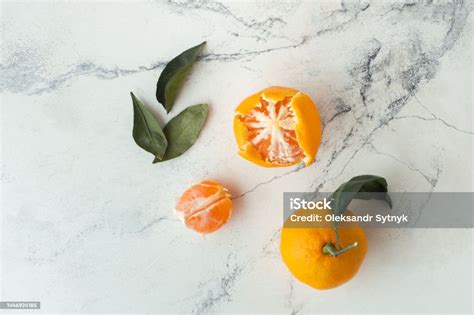 오렌지 육즙이 많은 귤 조각과 껍질을 벗긴 만다린이 흰색 대리석 배경에 흩어져 있습니다 플랫 레이 공간을 복사합니다 고리 버들 바구니에 신선한 여름 비타민이 풍부한 과일