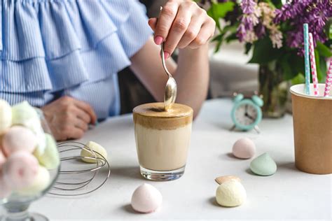 여자는 숟가락을 집어 들고 차가운 커피 한 잔에 두꺼운 휘핑 무스를 부드럽게 저어 부드러운 분위기와 맑은 아름다운 여름 아침 감정에 대한 스톡 사진 및 기타 이미지 Istock